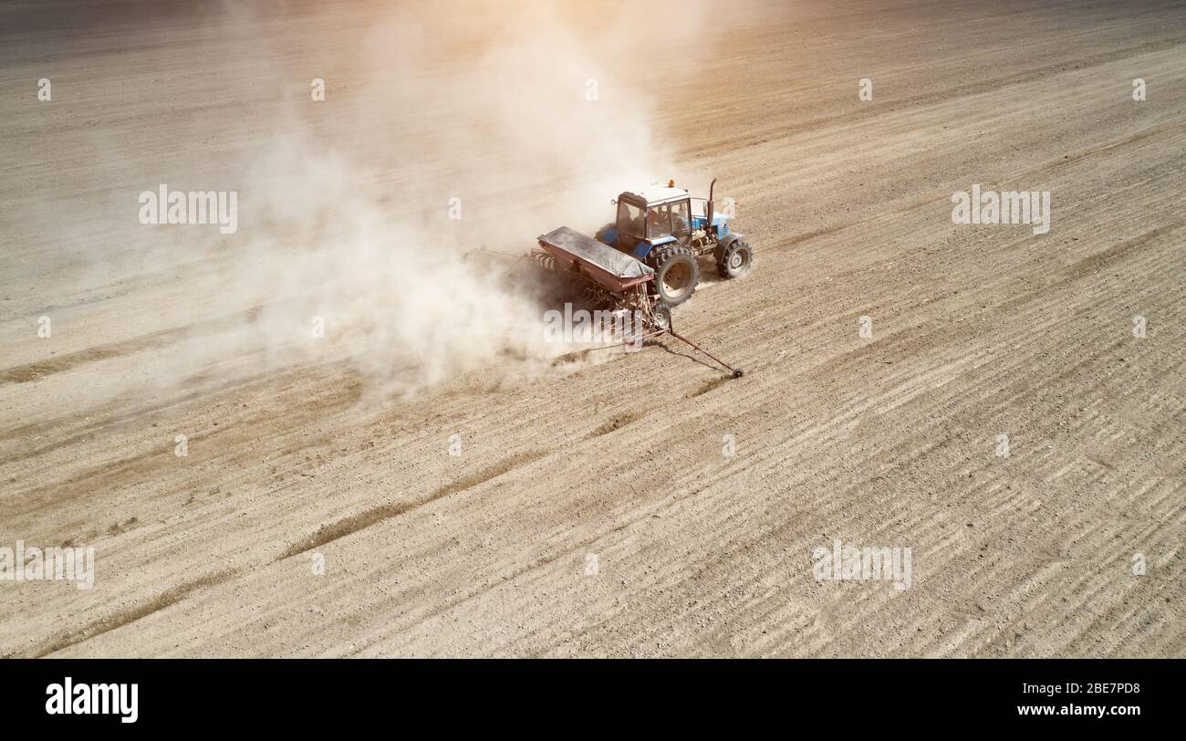 Aerial view of tractor with mounted seeder performing direct seeding of ...