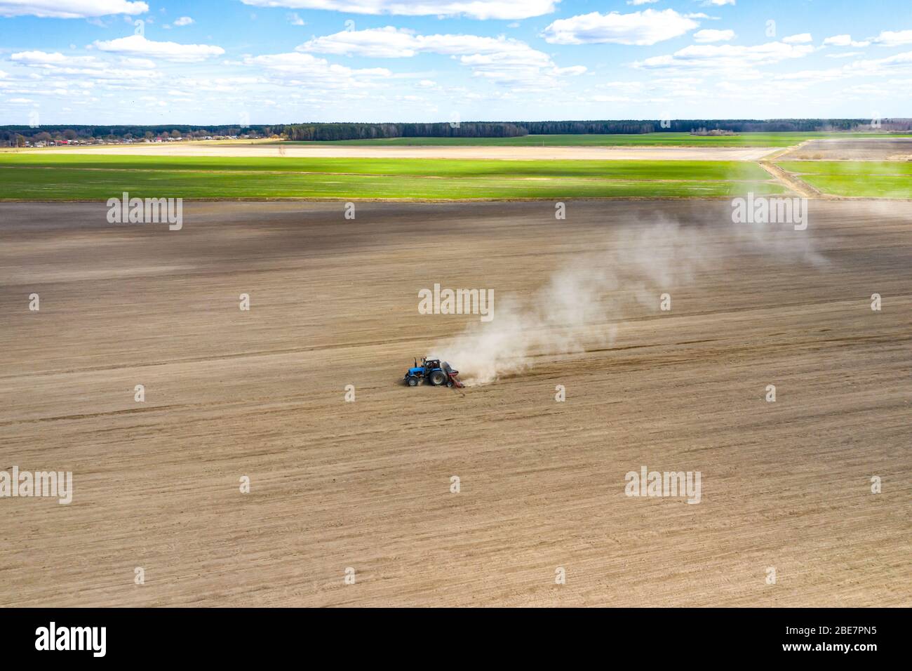 Aerial view of tractor with mounted seeder performing direct seeding of ...