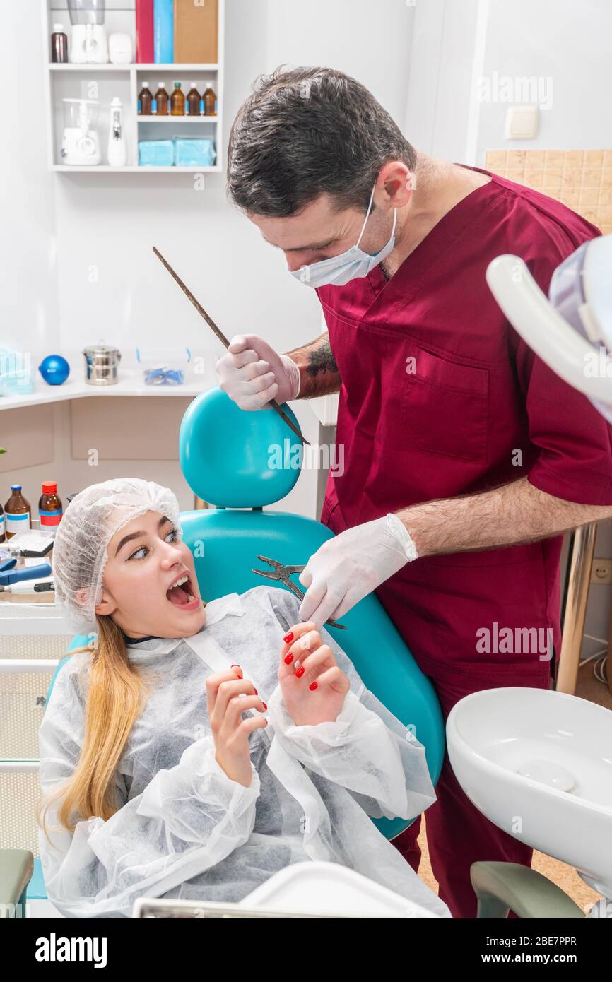 scared patient in a dentist chair is afraid of the doctor with pliers ...