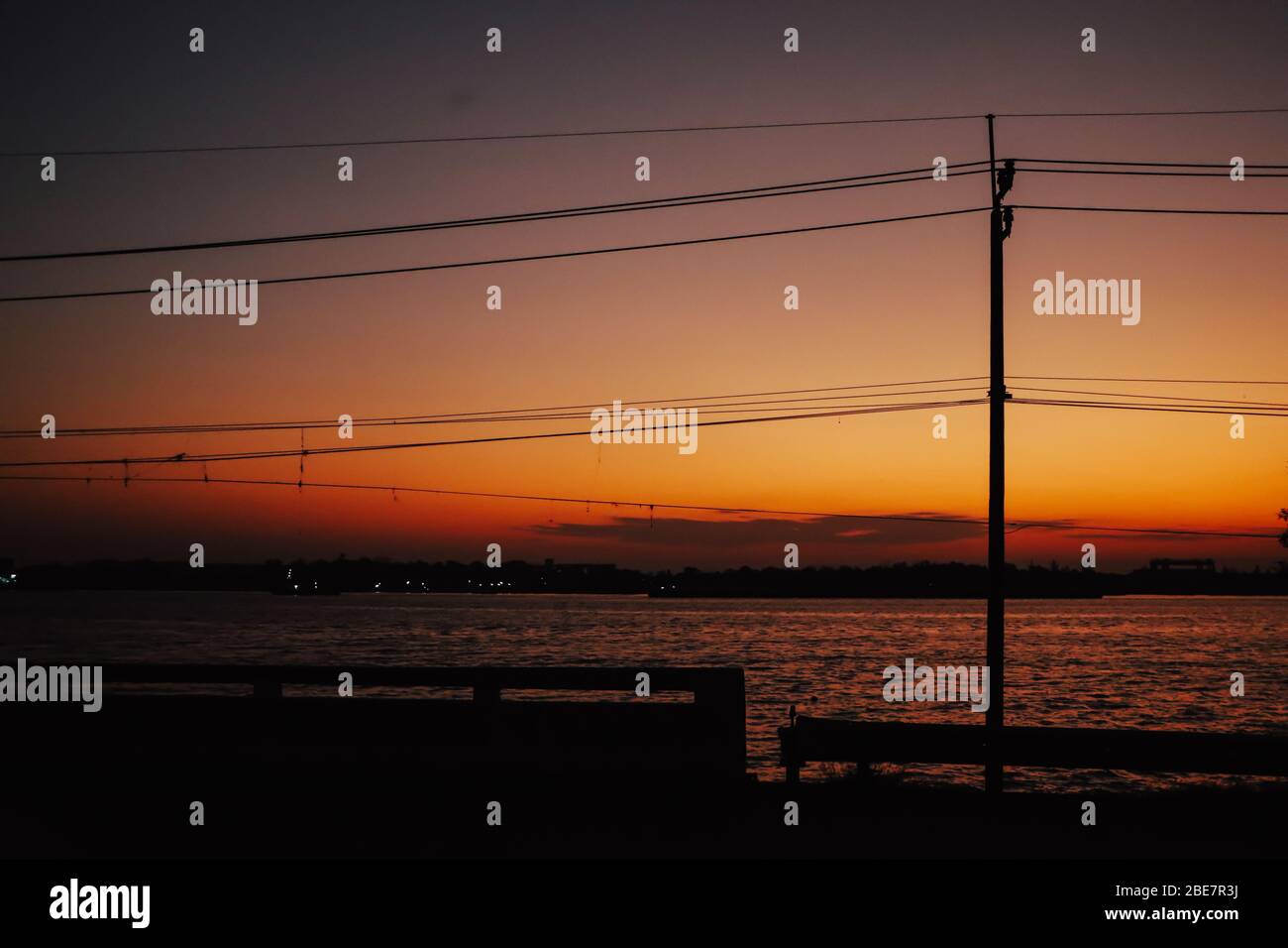 Electricity pylons with wire cable and street lamp post at sunset ...
