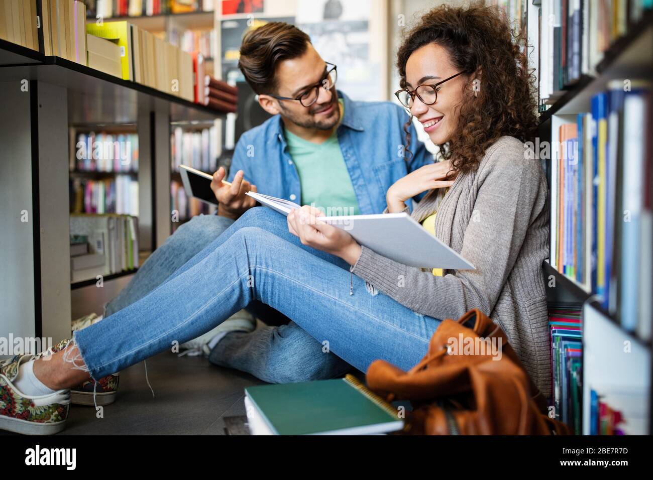Group of happy students reading books and preparing to exam in library ...