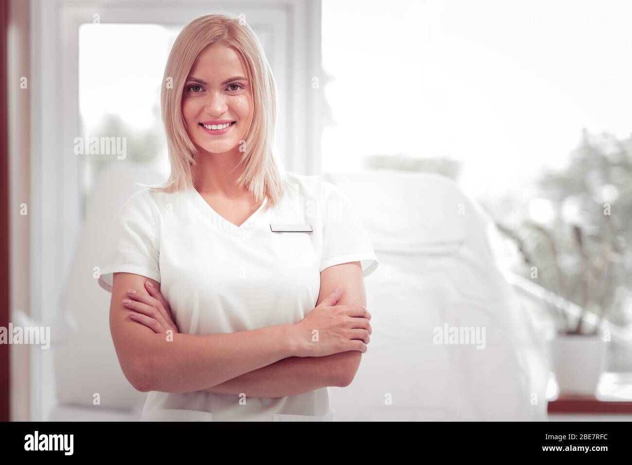 Expert smiling. Beauty expert wearing white uniform smiling after ...