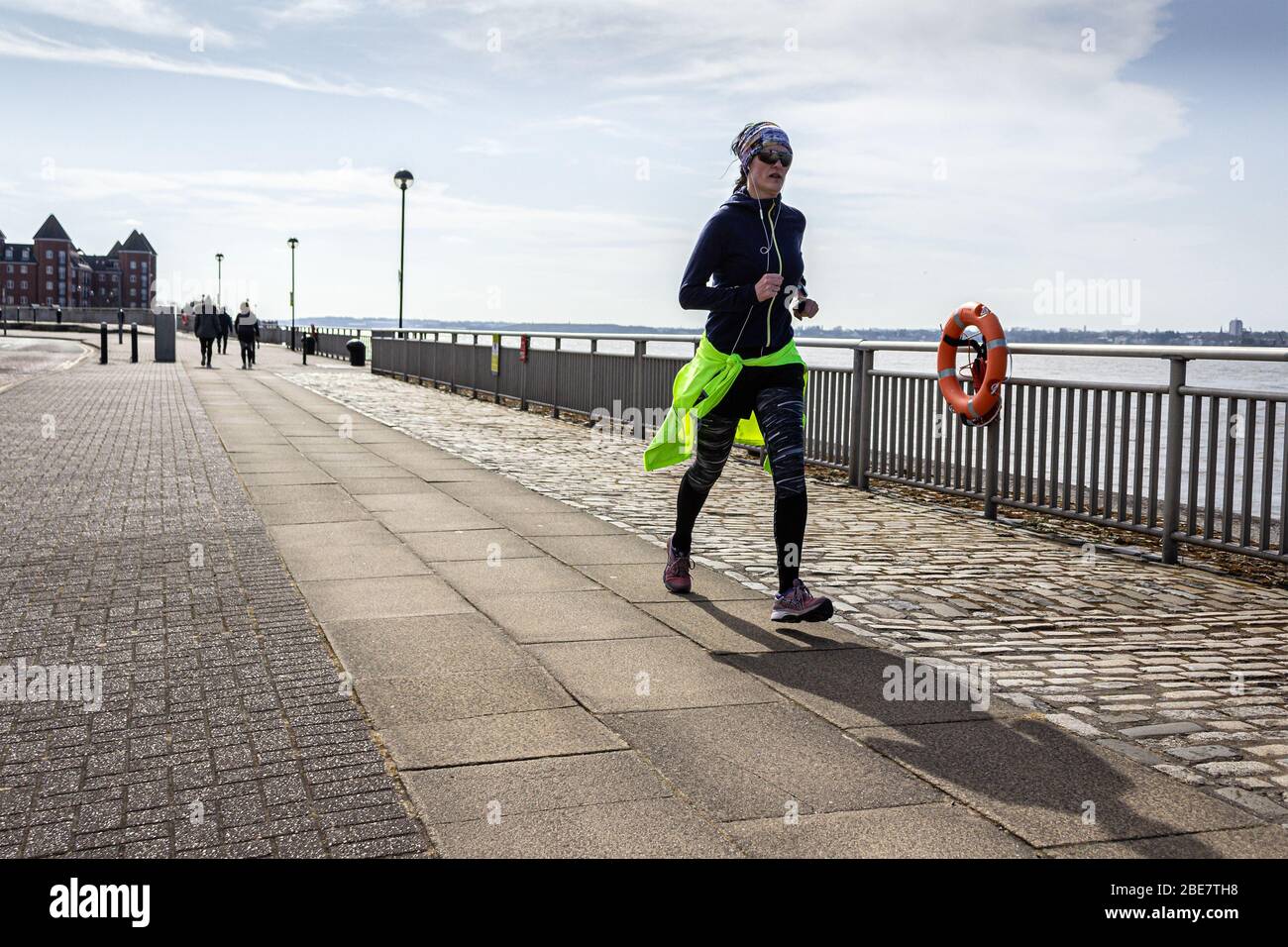 Jogger running along the Mersey waterfront on Kings Parade, Liverpool ...
