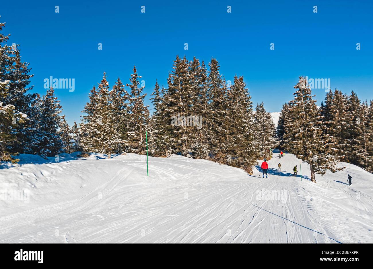 Panoramic landscape valley view with skiers going down a ski slope ...