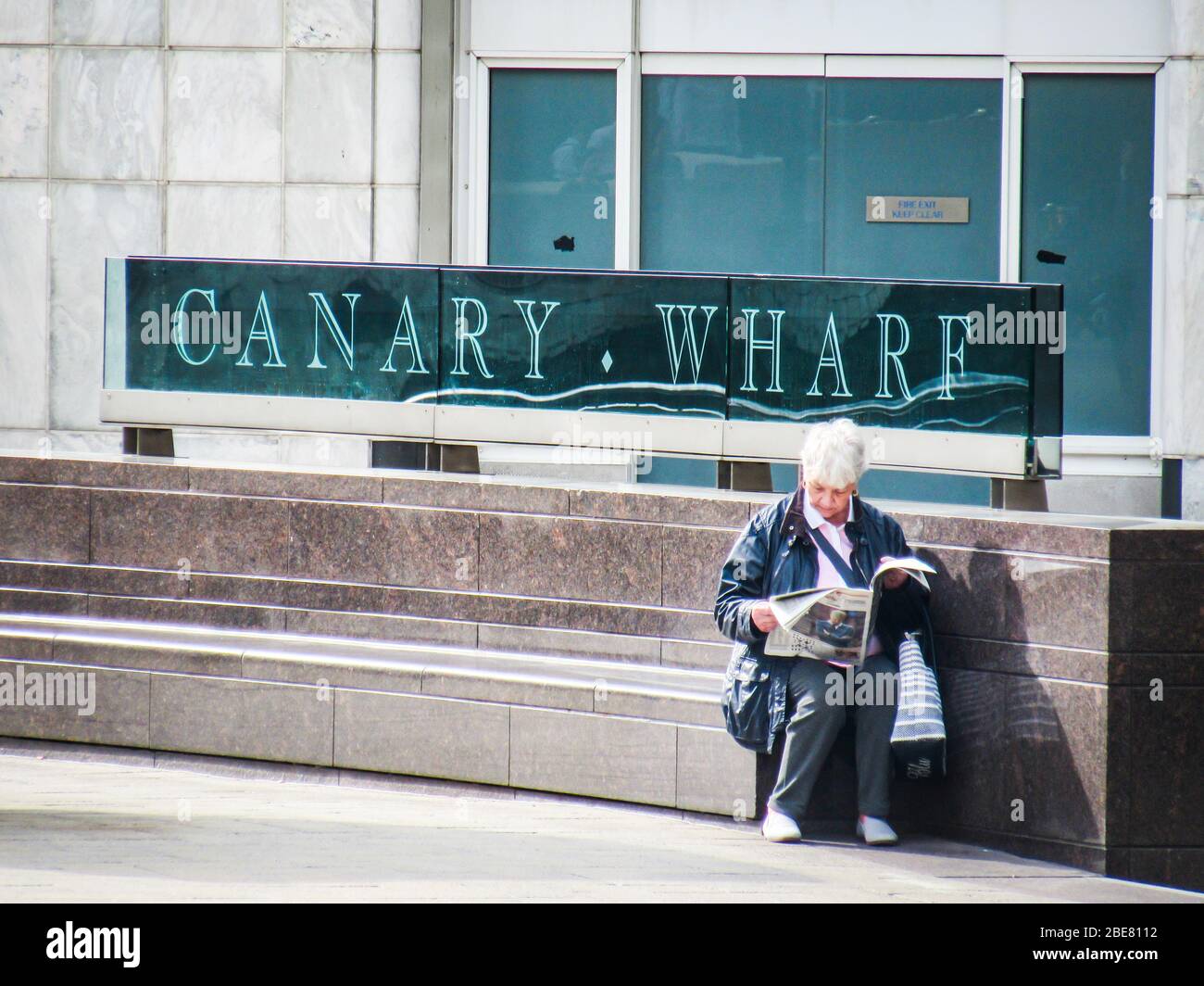 Canary Wharf - London: Woman sitting and reading newspaper in front of ...