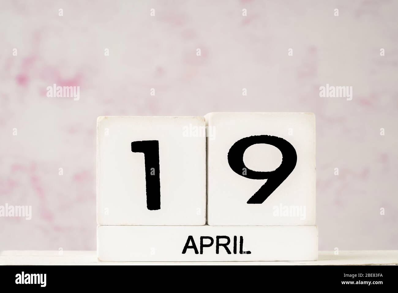 White cube calendar for April against soft pink background with copy ...