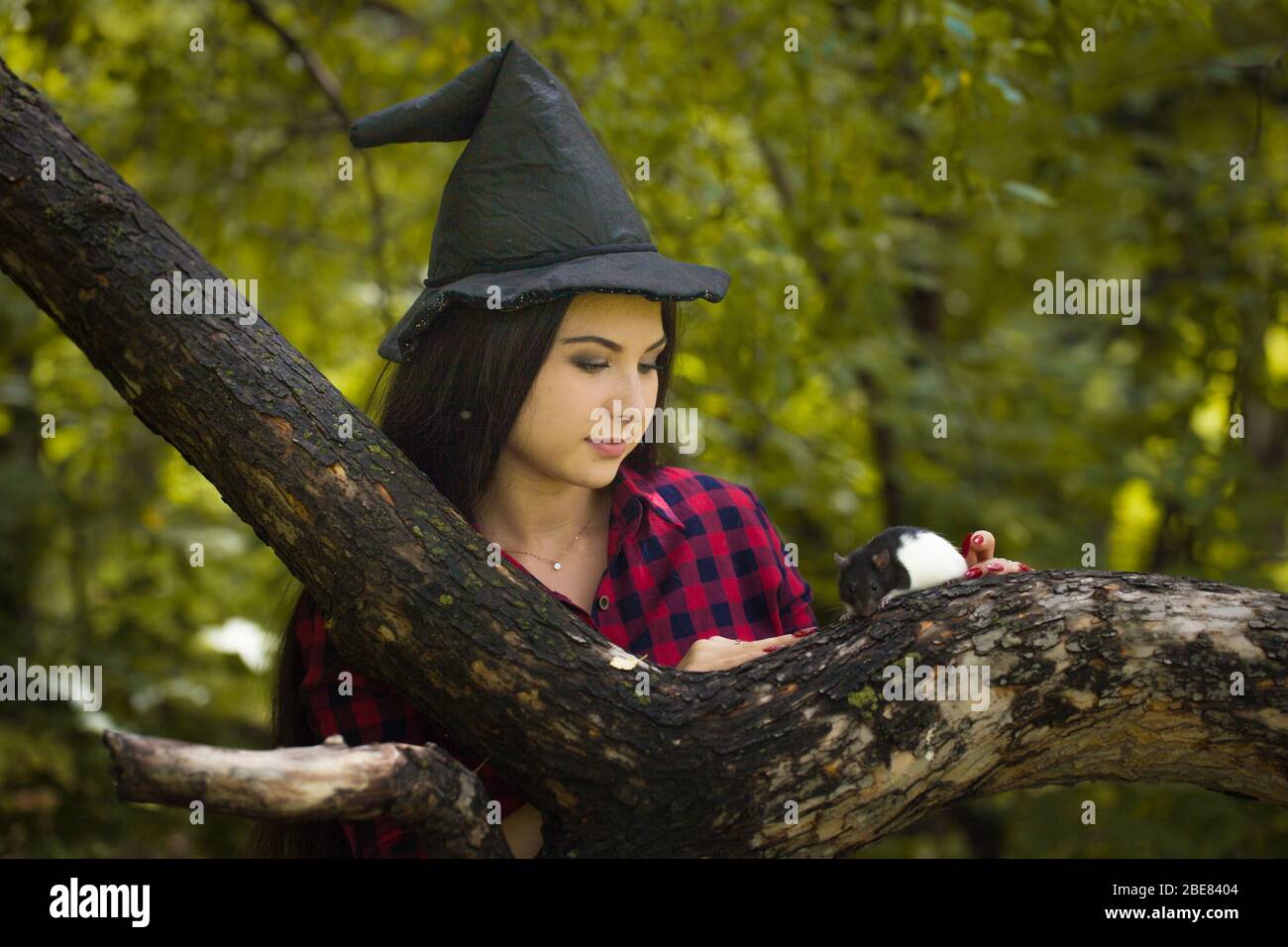 Witch conjures in the woods with a familiar. Brunette girl with a rat ...
