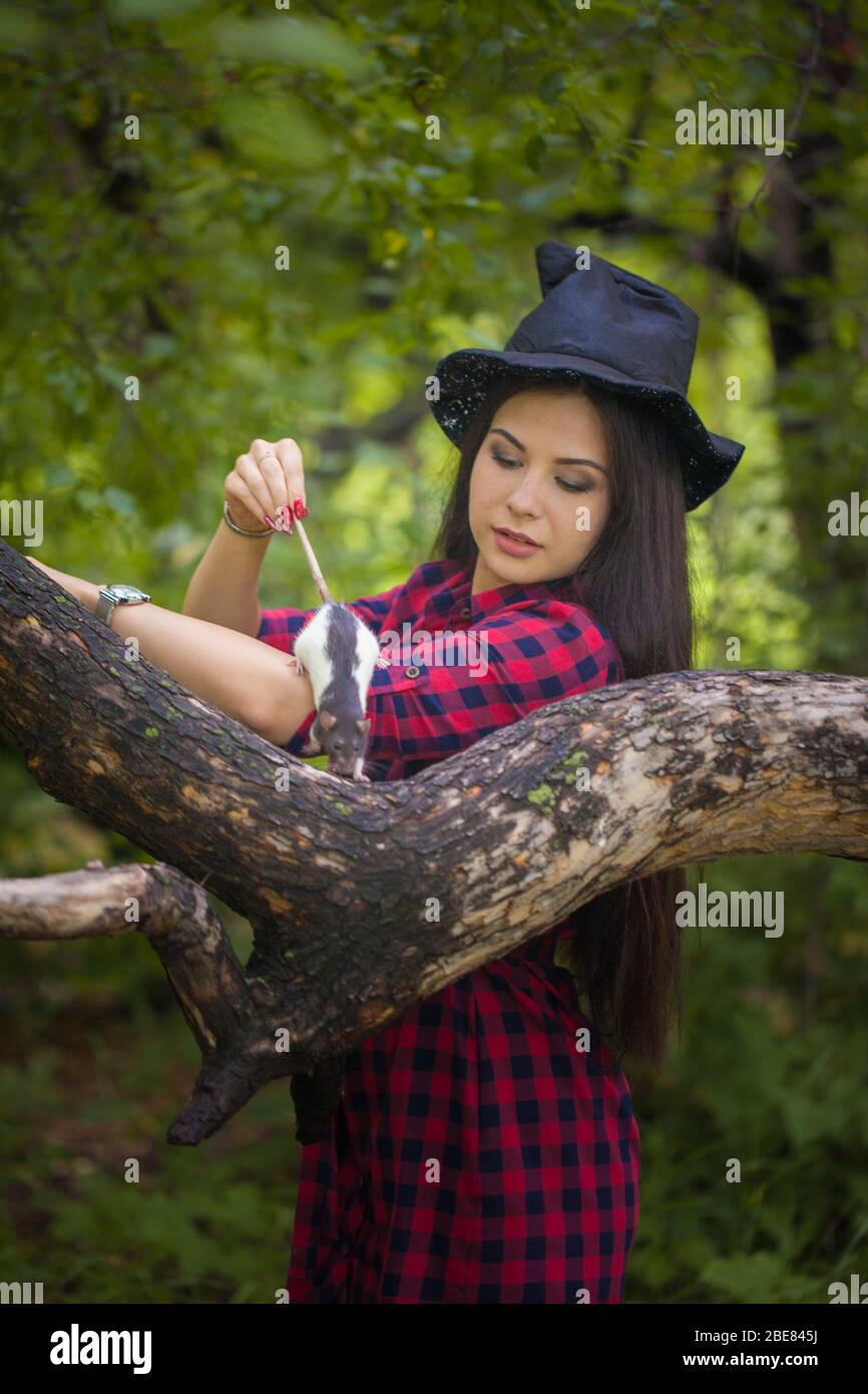 Witch conjures in the woods with a familiar. Brunette girl with a rat ...