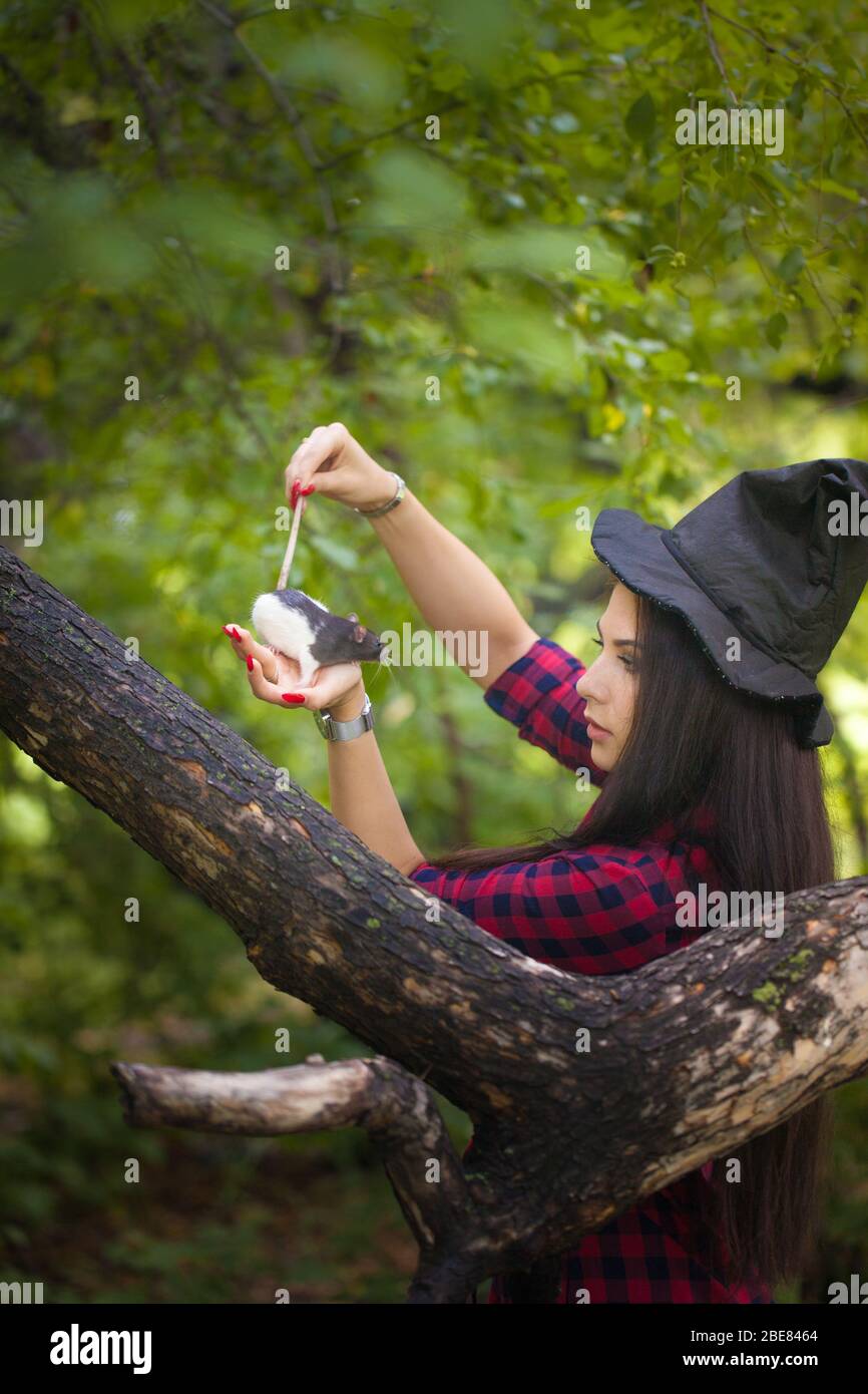 Witch conjures in the woods with a familiar. Brunette girl with a rat ...