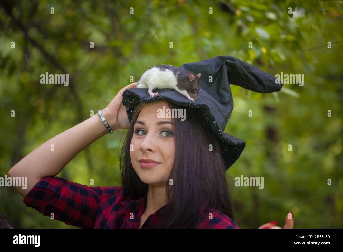 Witch conjures in the woods with a familiar. Brunette girl with a rat ...