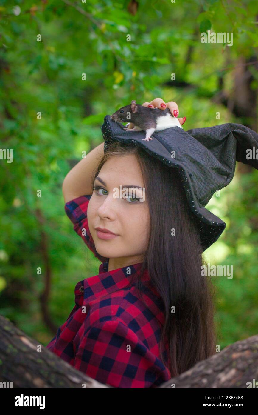 Witch conjures in the woods with a familiar. Brunette girl with a rat ...