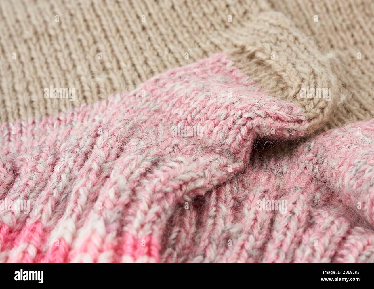 fragment of knitted socks from beige and pink woolen thread, close up ...
