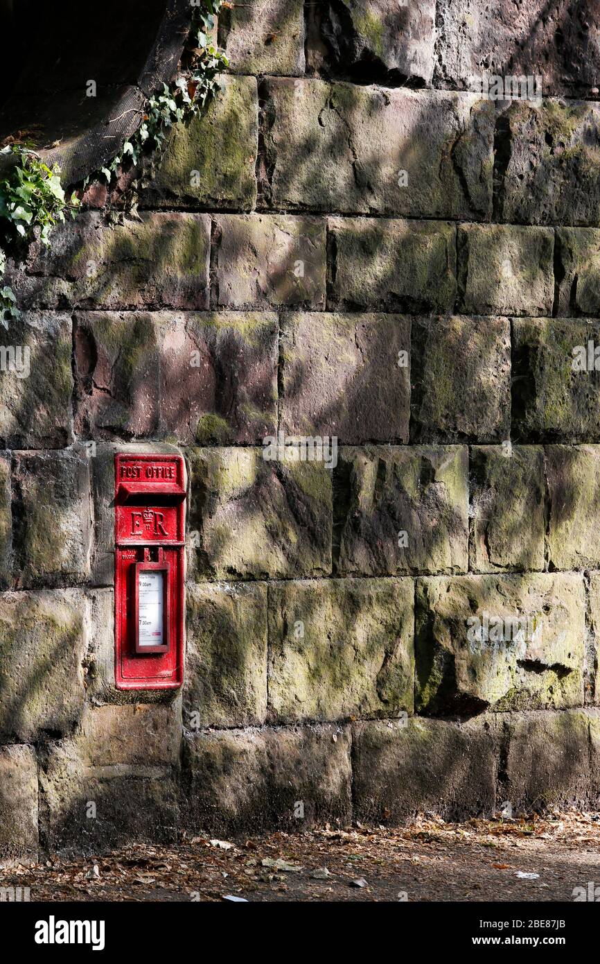 A traditional red post box installed in a sandstone wall in Woolton ...