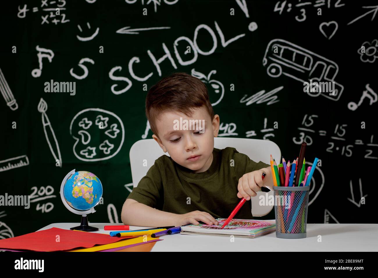 Cute child boy doing homework. Clever kid drawing at desk. Schoolboy ...
