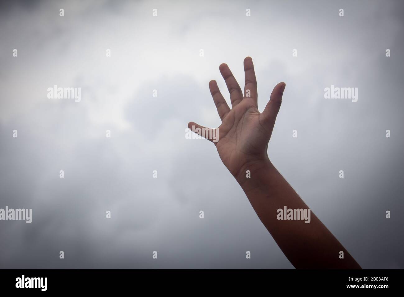 Hand raised high with sky in background Stock Photo - Alamy