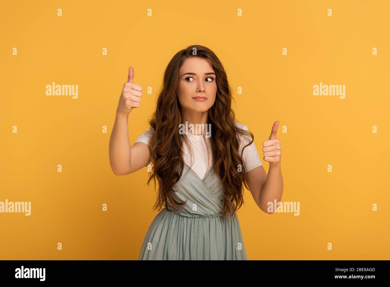 beautiful smiling spring woman showing thumbs up isolated on yellow ...
