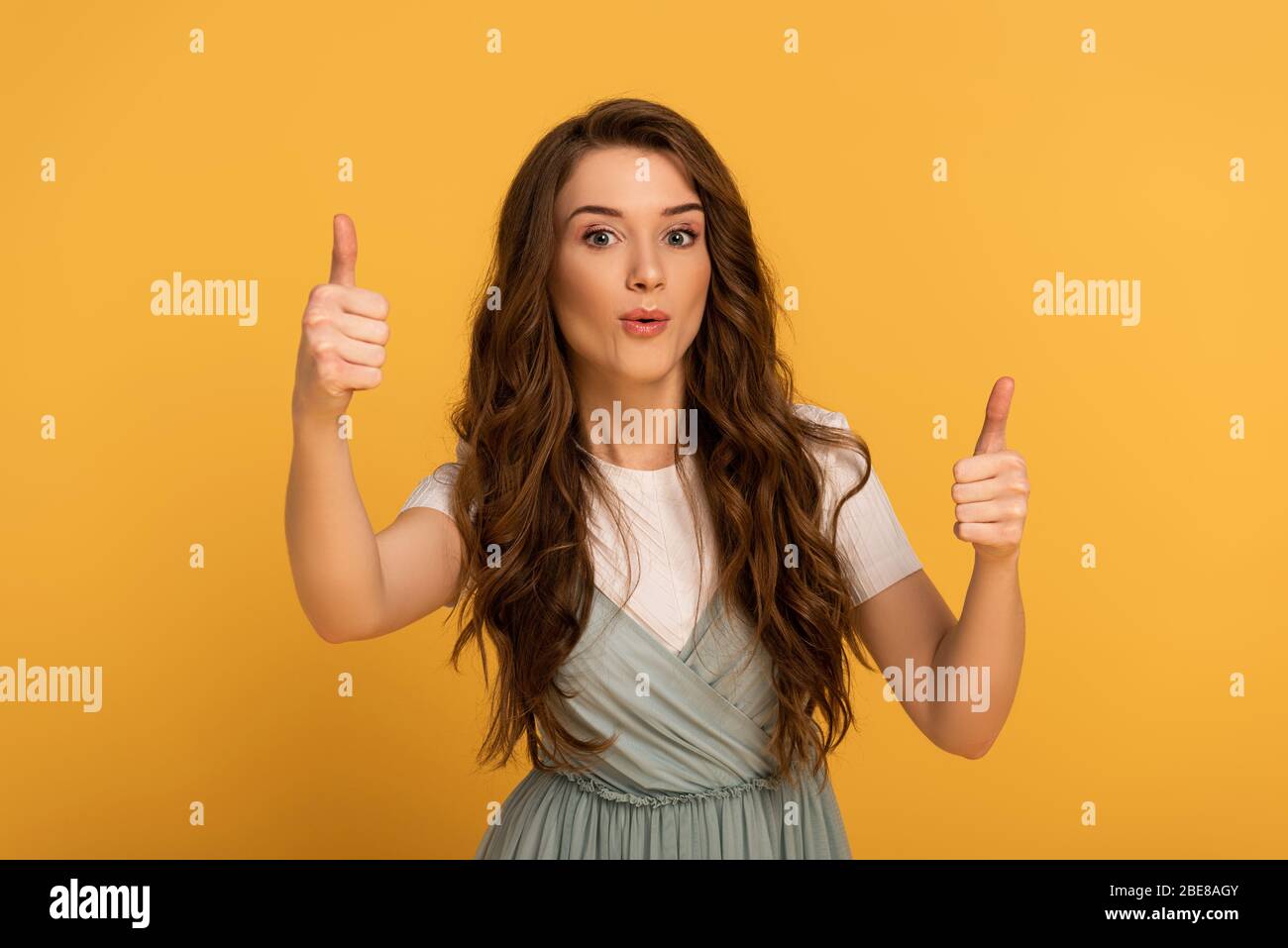 beautiful surprised spring woman showing thumbs up isolated on yellow ...