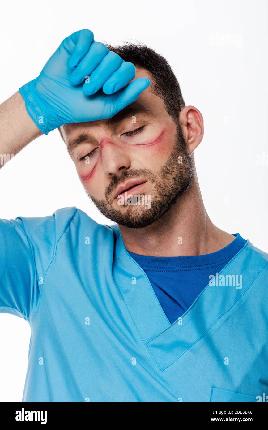 tired doctor with marks on face and closed eyes touching forehead ...