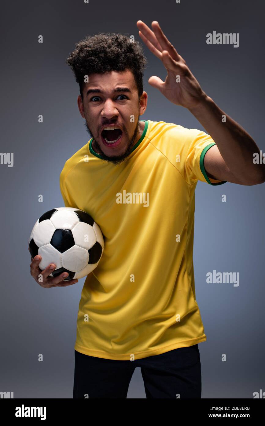 aggressive african american football fan in yellow t-shirt shouting and ...