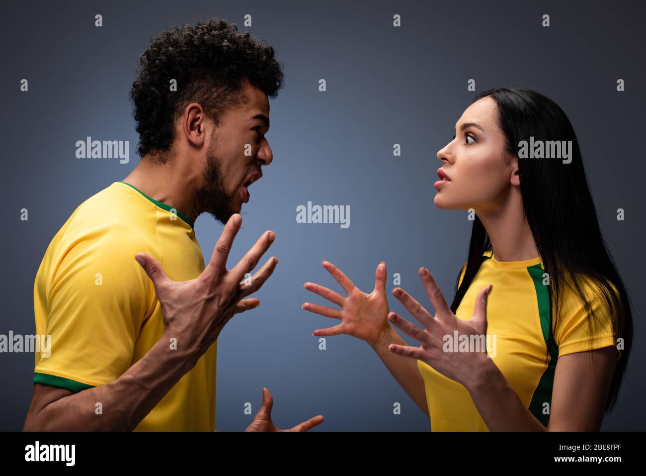 aggressive multicultural couple of football fans in yellow t-shirts ...