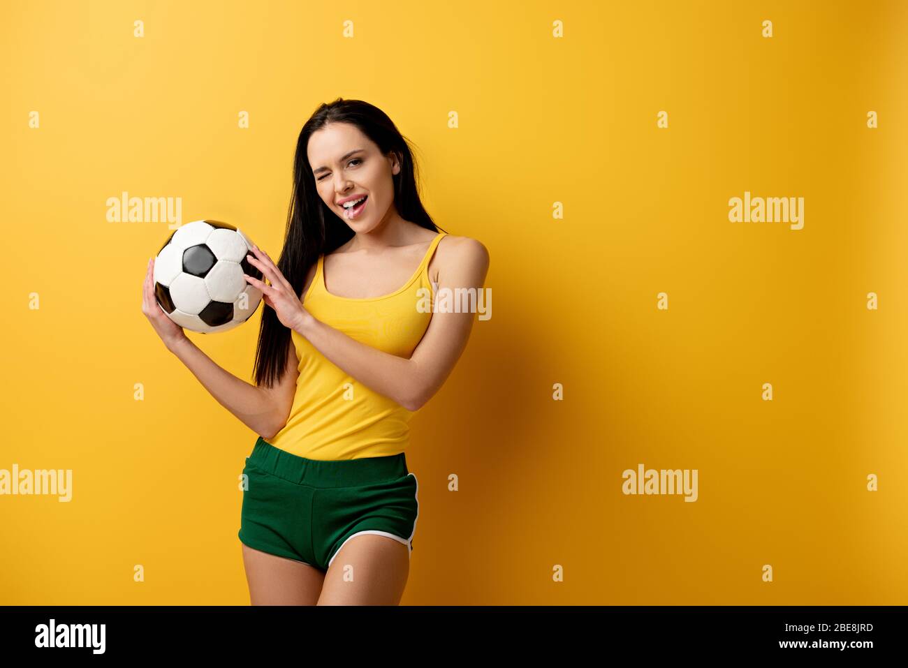 beautiful cheerful female football fan winking and holding ball on ...