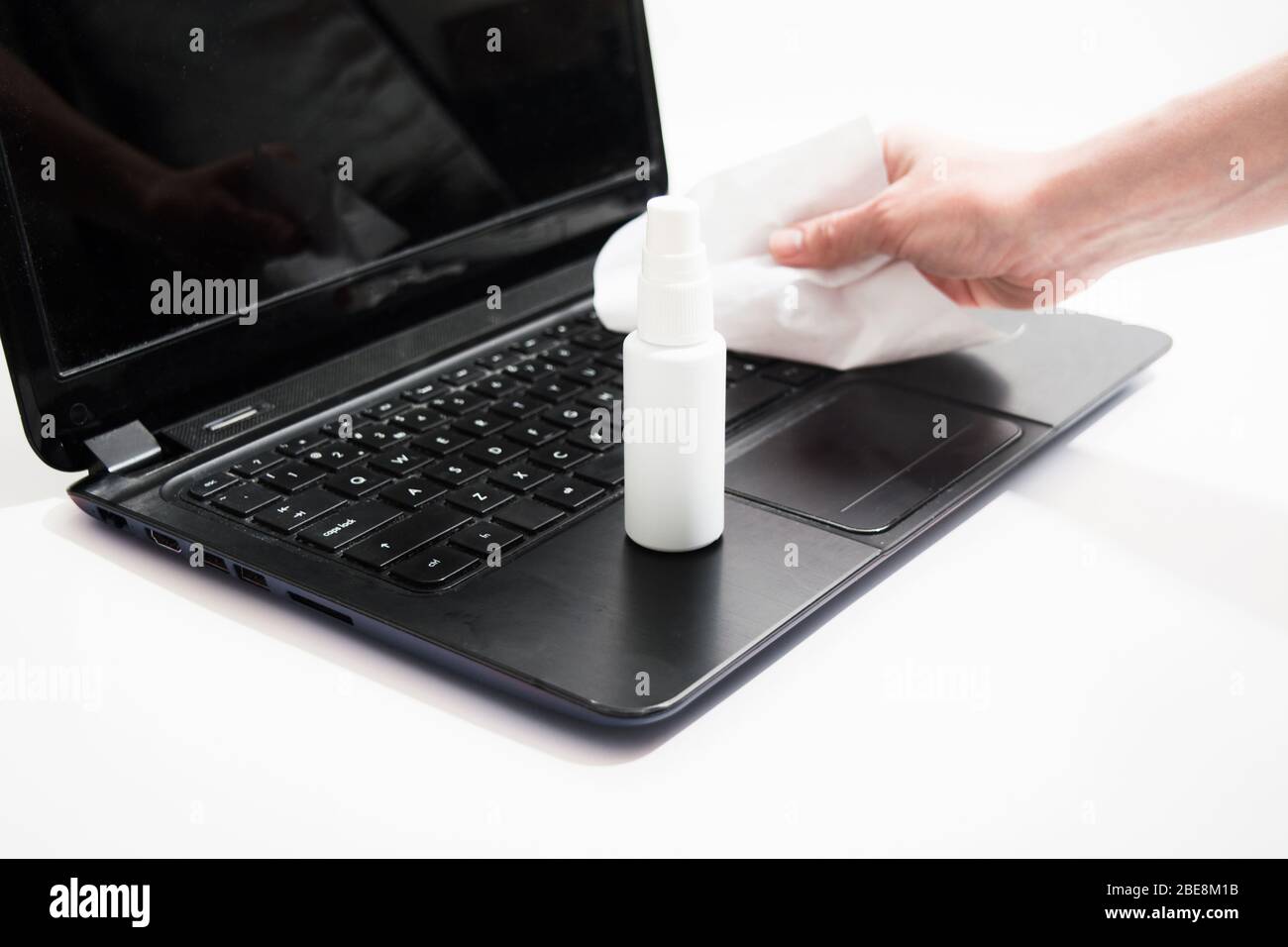 Woman hand wipe laptop with liquid for cleaning and prevention of virus ...