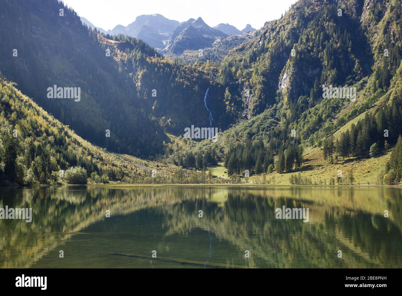 Enchanting valley with reflecting lake water and waterfall in the ...