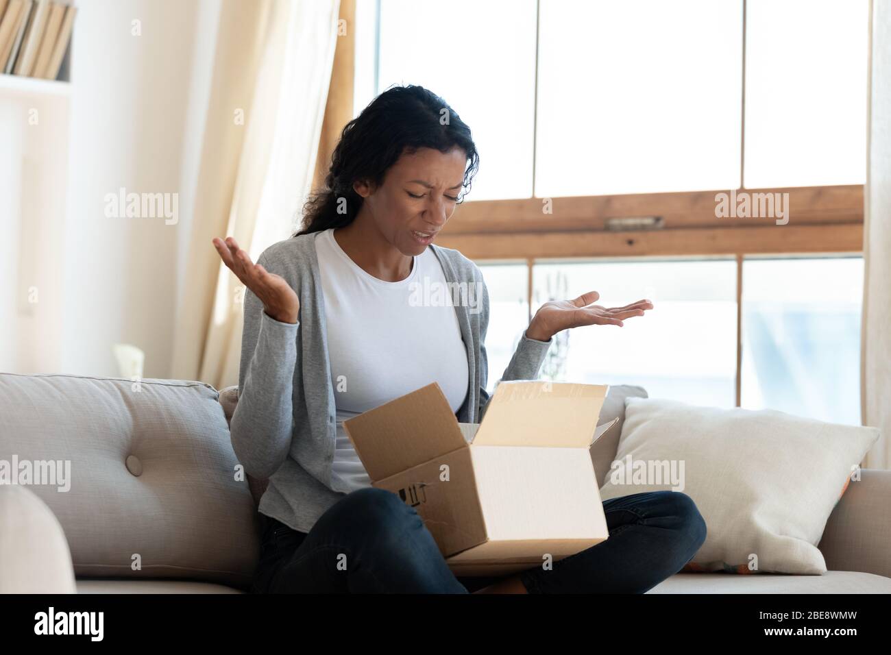 Disappointed black young girl open a cardboard box Stock Photo - Alamy