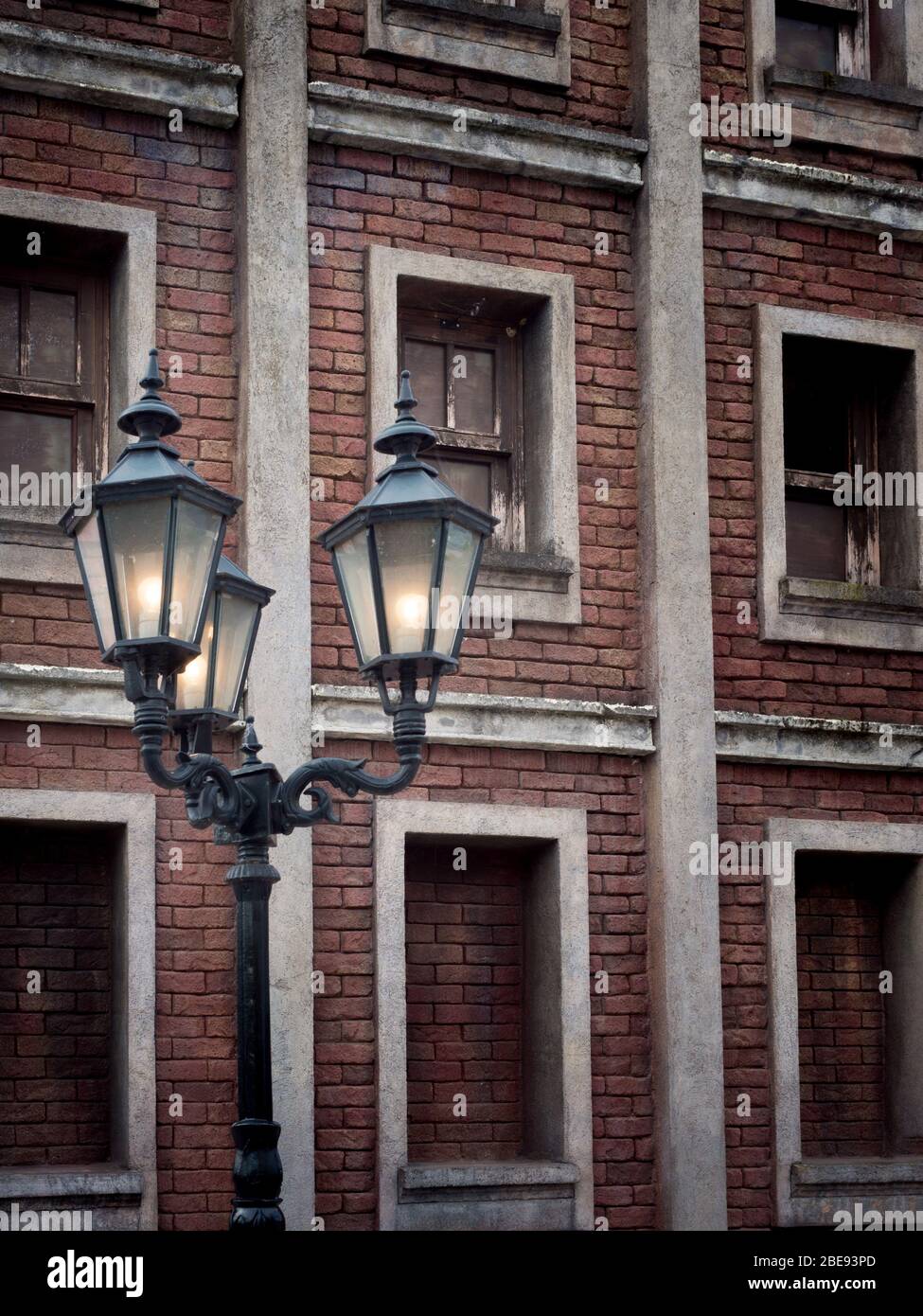 Facade of old abandoned brick house. Windows divided by white squares ...