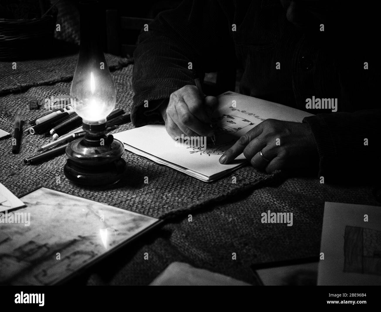 A man draws in a dark and poor room in the light of an oil lantern ...