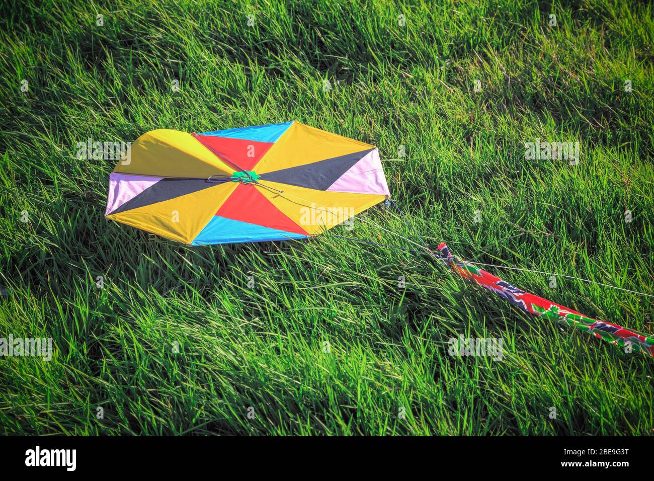 Fallen colourful kite on grass for concept use Stock Photo - Alamy