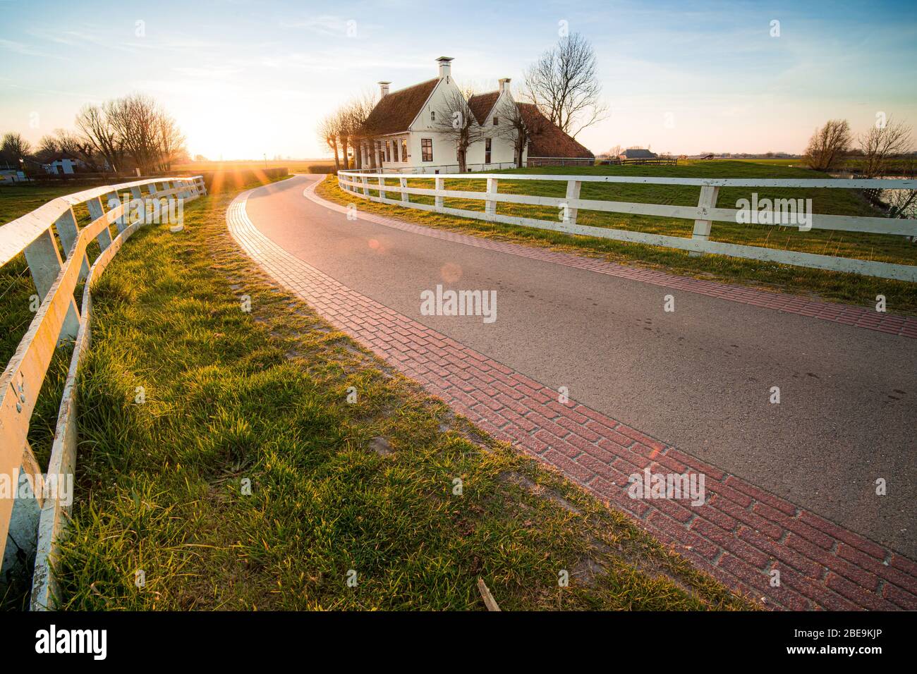 Dutch landscape with historical houses in evening along a curved road ...