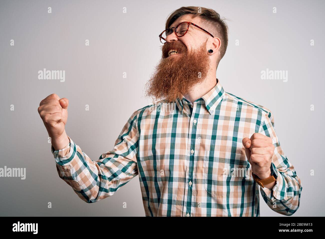 Handsome Irish redhead man with beard wearing glasses and hipster shirt ...