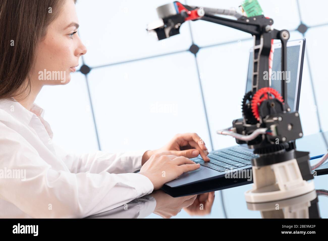A young woman writes an algorithm for the robot arm. Science Research ...