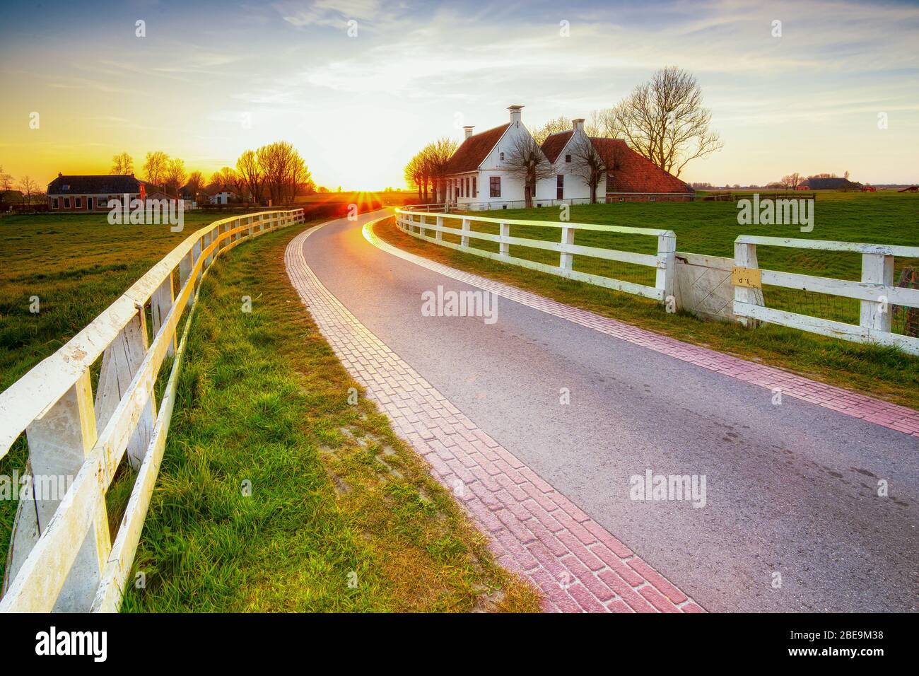 Dutch landscape with historical houses in evening along a curved road ...