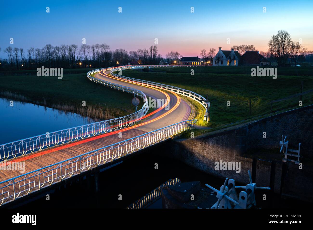 Curved Asphalt country road in dutch countryside with white fence ...