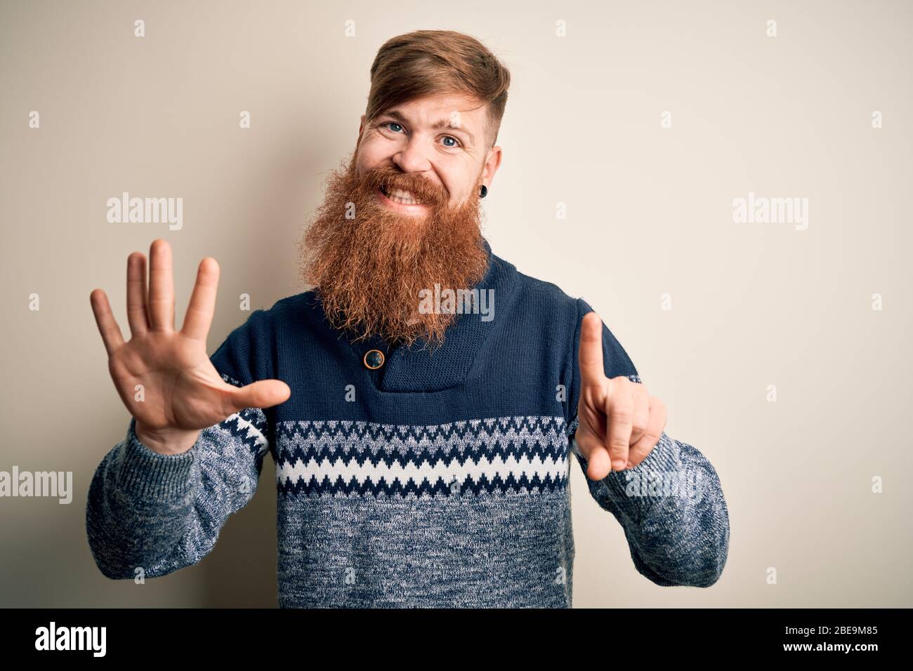 Handsome Irish redhead man with beard wearing winter sweater over ...