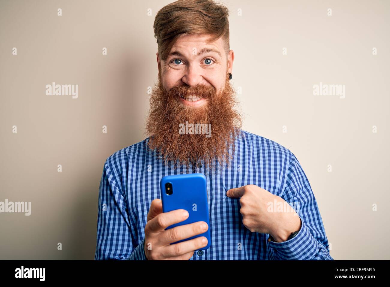 Redhead Irish man with beard using smartphone looking at screen over ...
