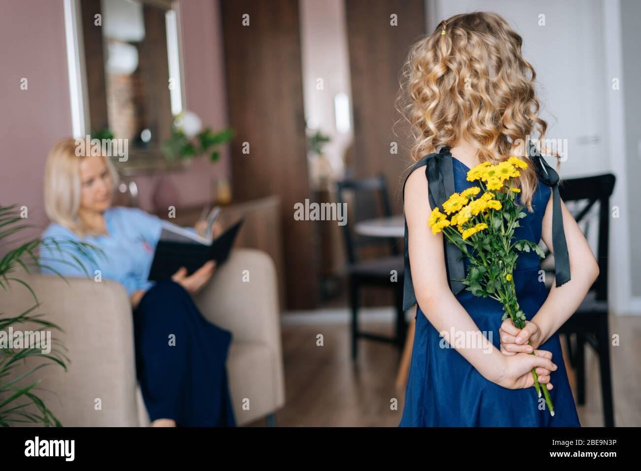 Rear view of adorable daughter hiding behind back surprise for her ...