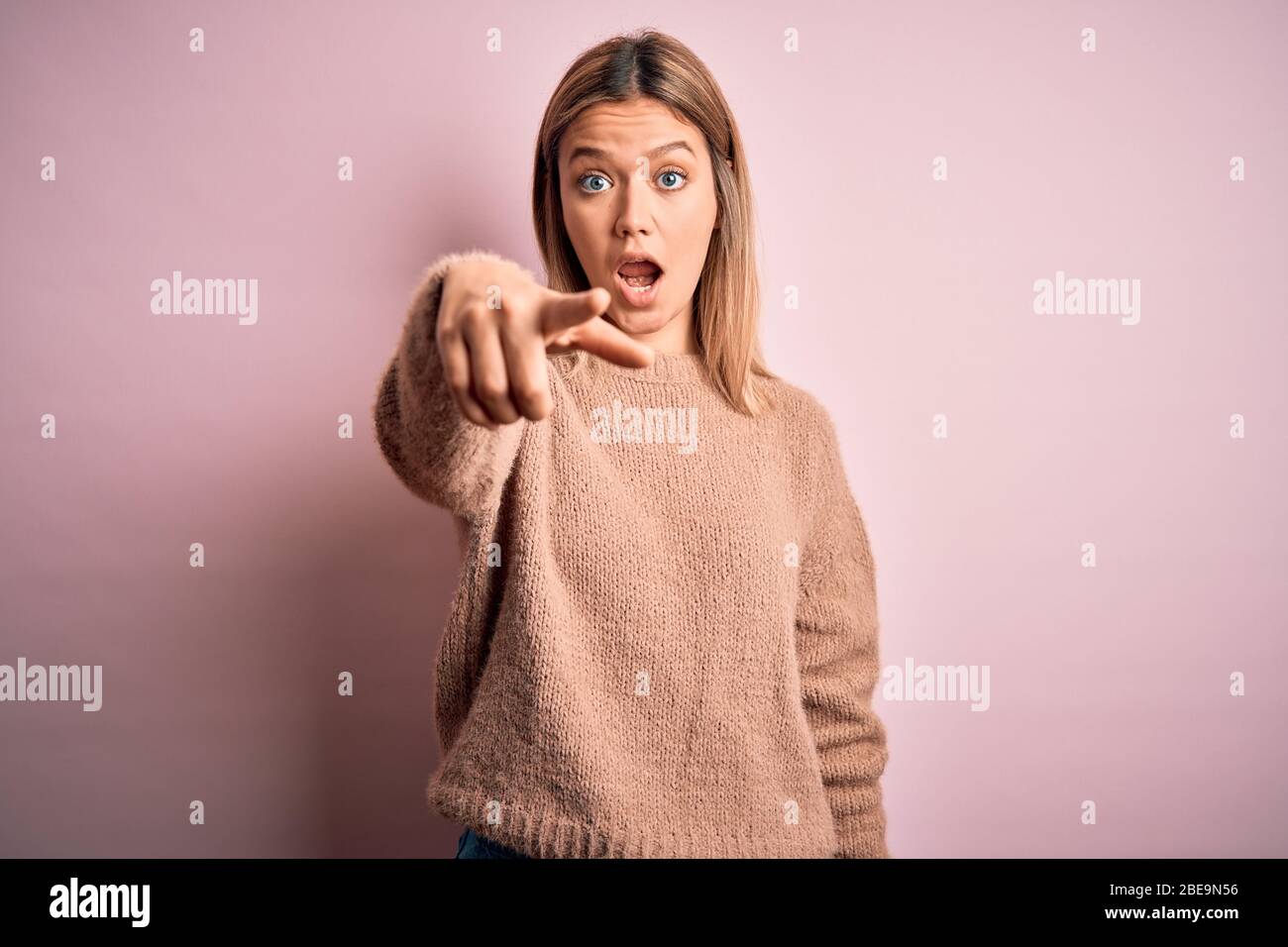 Young beautiful blonde woman wearing winter wool sweater over pink ...