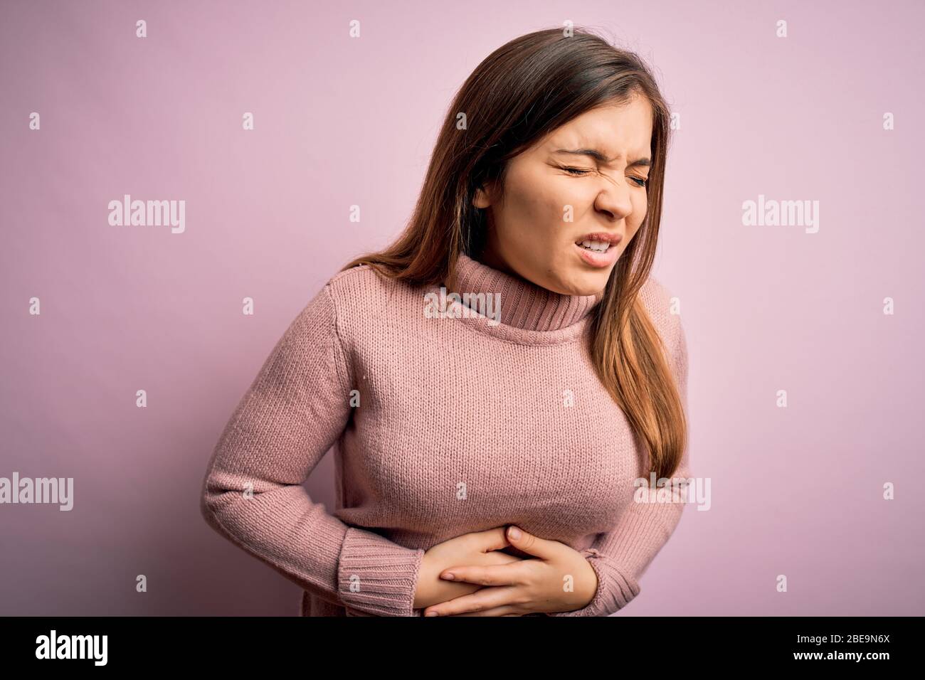 Beautiful young woman wearing turtleneck sweater over pink isolated ...