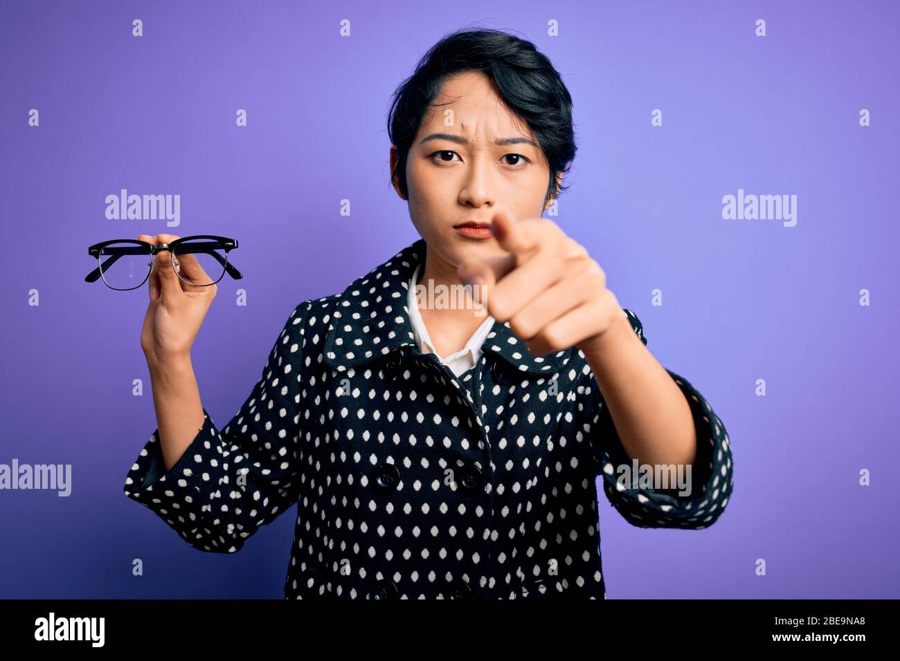 Young beautiful asian optical girl holding vision glasses over isolated ...