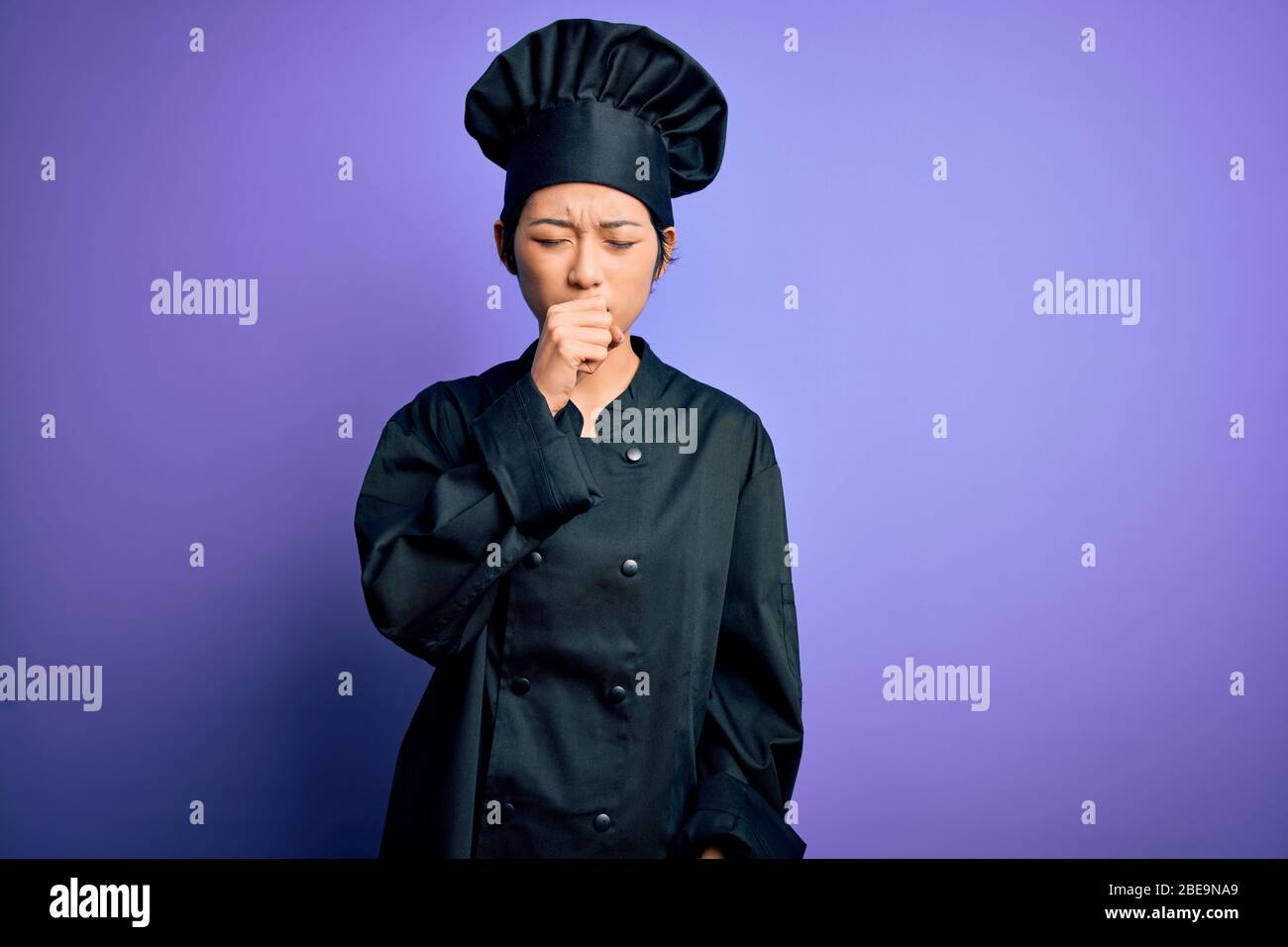 Young beautiful chinese chef woman wearing cooker uniform and hat over ...