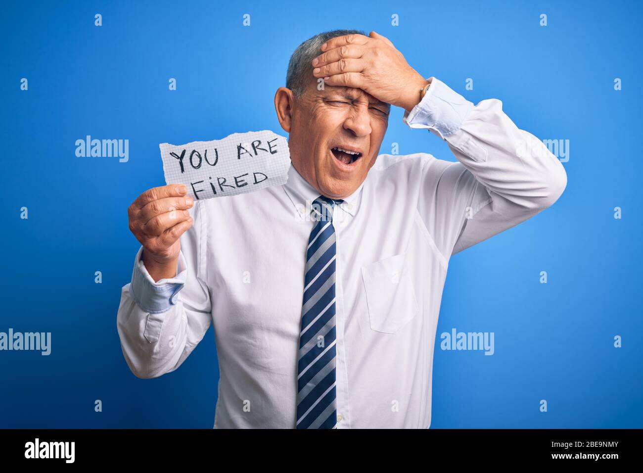 Senior handsome businessman holding you are fired paper over isolated ...