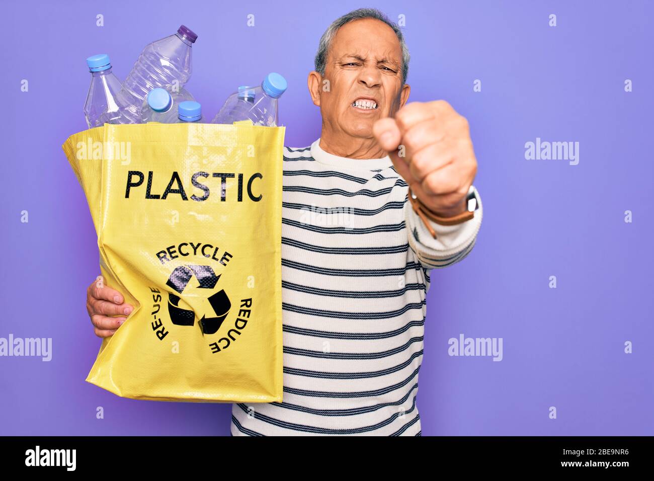 Senior man recycling holding bag with plastic bottles to recycle over ...