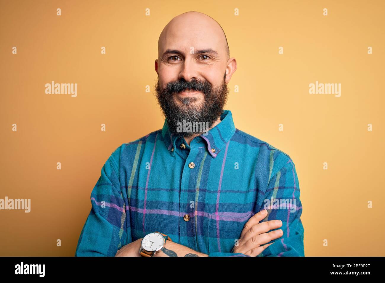 Handsome bald man with beard wearing casual shirt standing over ...