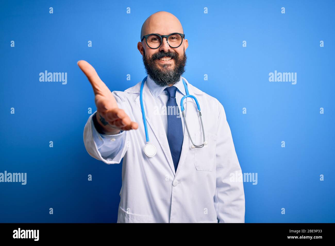 Handsome bald doctor man with beard wearing glasses and stethoscope ...
