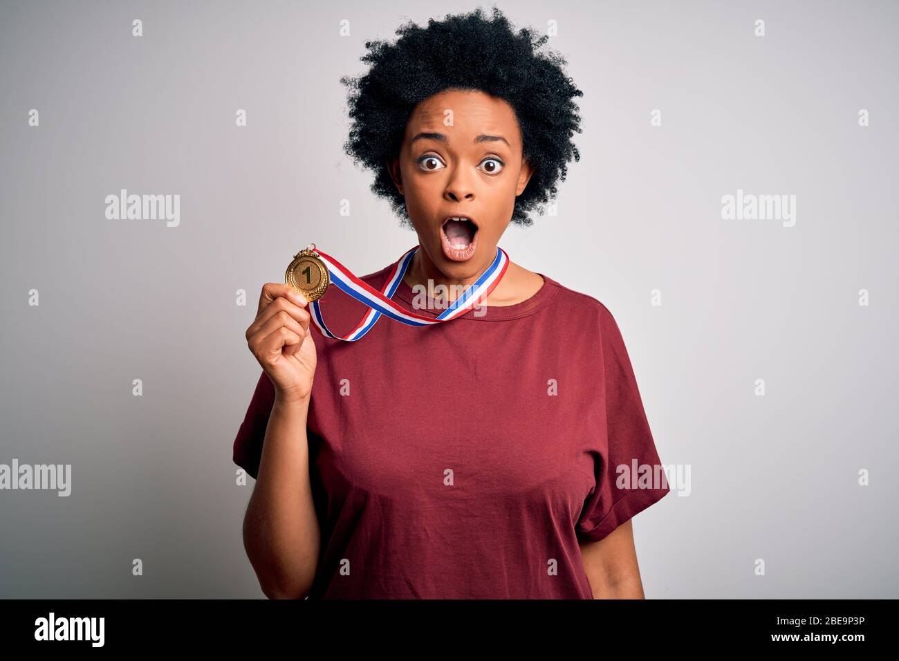 Young African American athlete woman with curly hair wearing gold medal ...