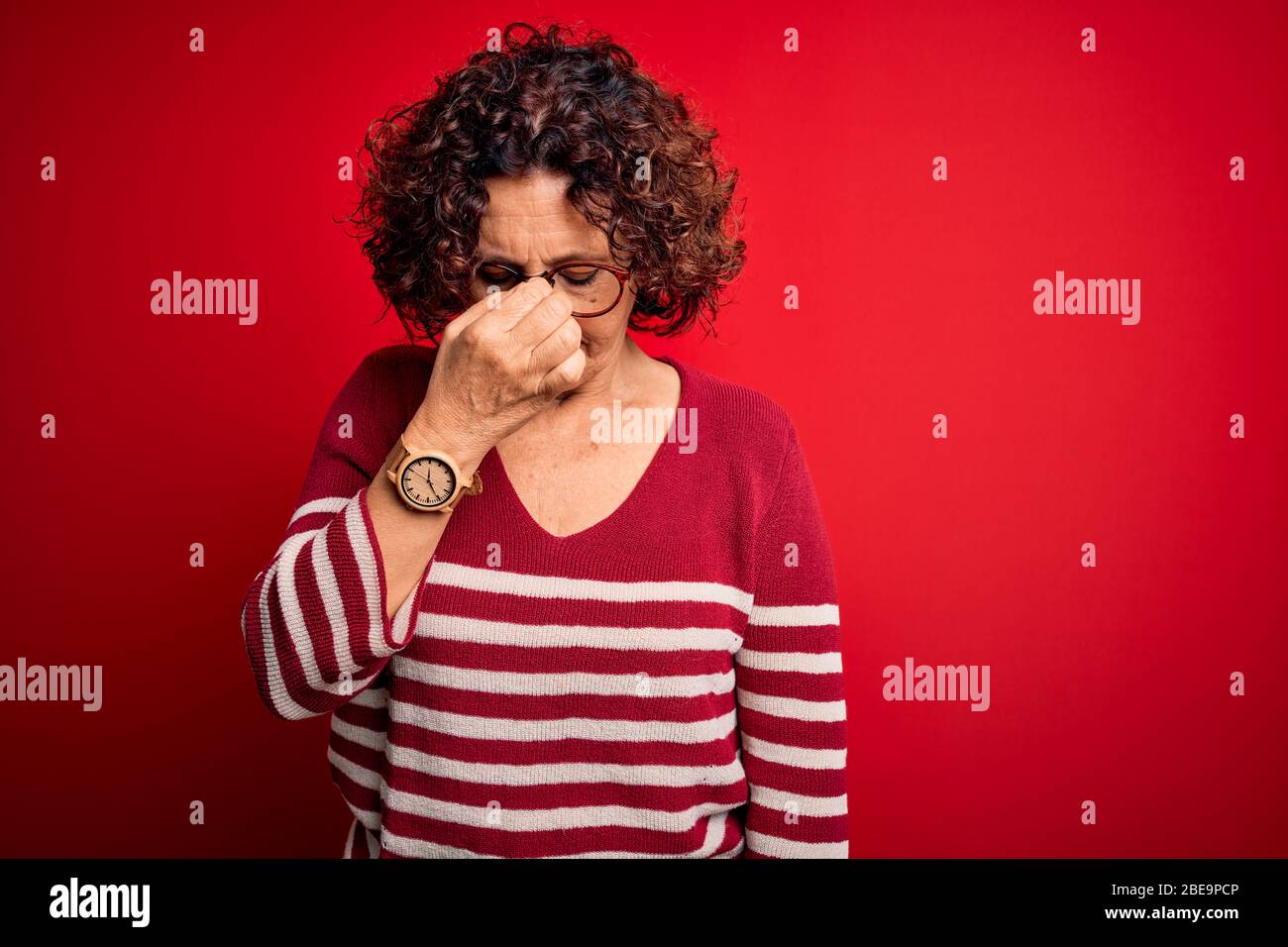 Middle age beautiful curly hair woman wearing casual striped sweater ...