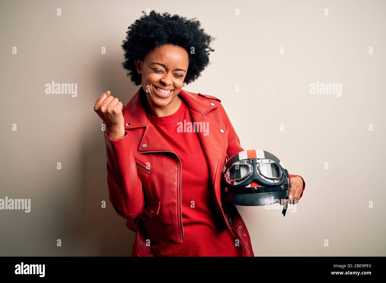Young African American afro motorcyclist woman with curly hair holding ...